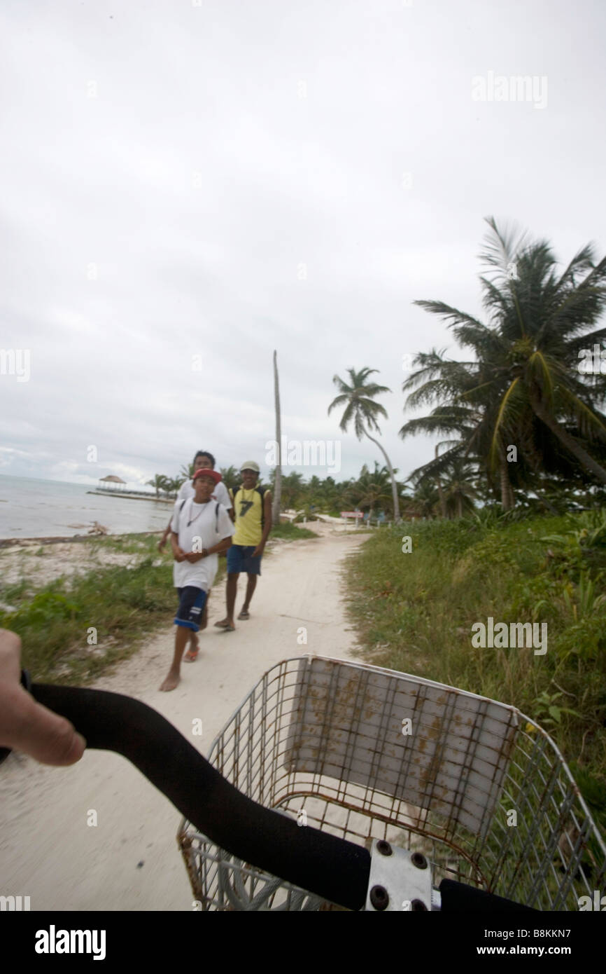 Three young native Belizean teenagers walk the beach while seen from a ...