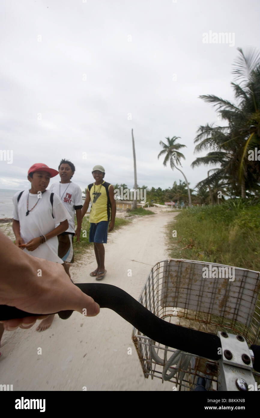 Three young native Belizean teenagers walk the beach while seen from a ...