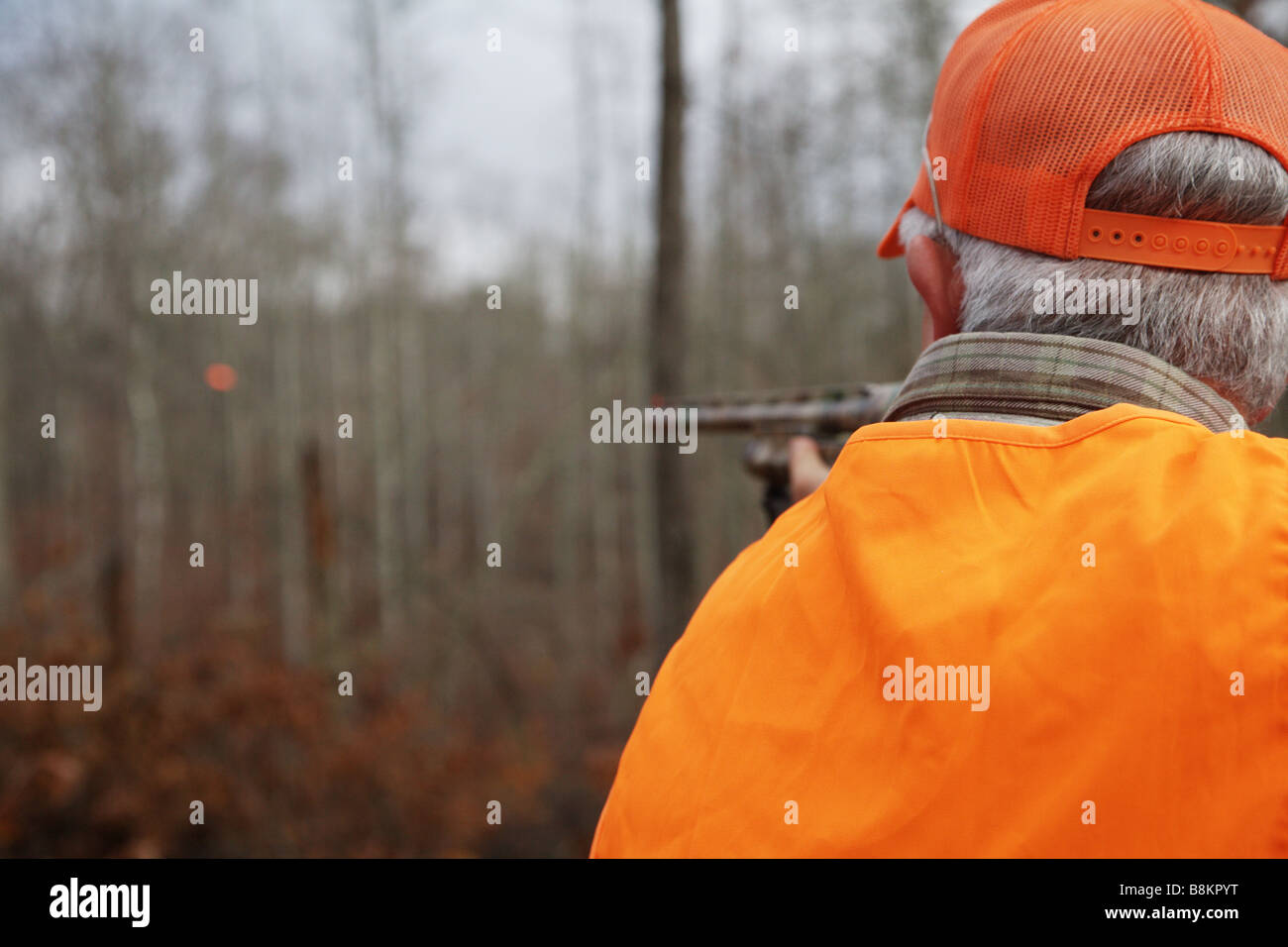 CLOSEUP OVER THE SHOULDER VIEW OF SPORTING CLAY SHOOTER FIRING AT A ...