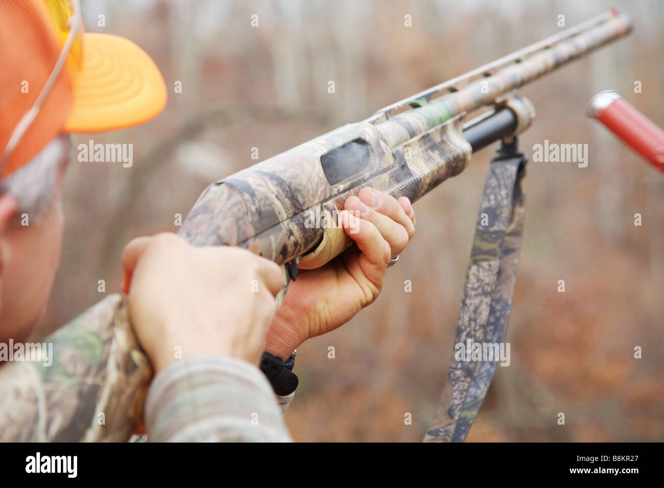 CLOSEUP OVER THE SHOULDER VIEW OF SPORTING CLAY SHOOTER FIRING AT A ...