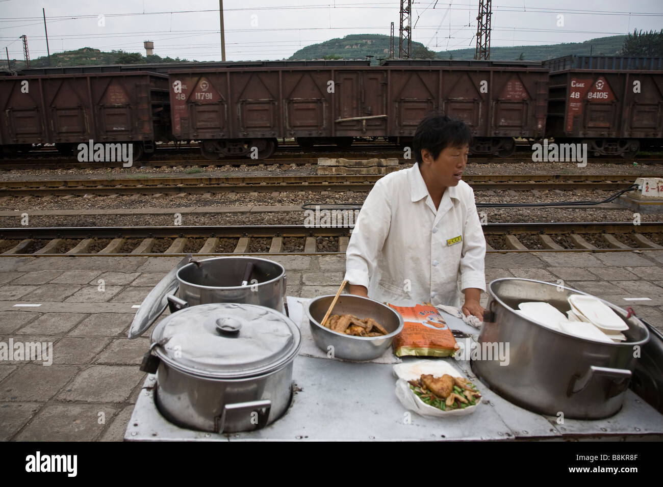 Chinese cook at his hawker stall on the platform of a train station in ...
