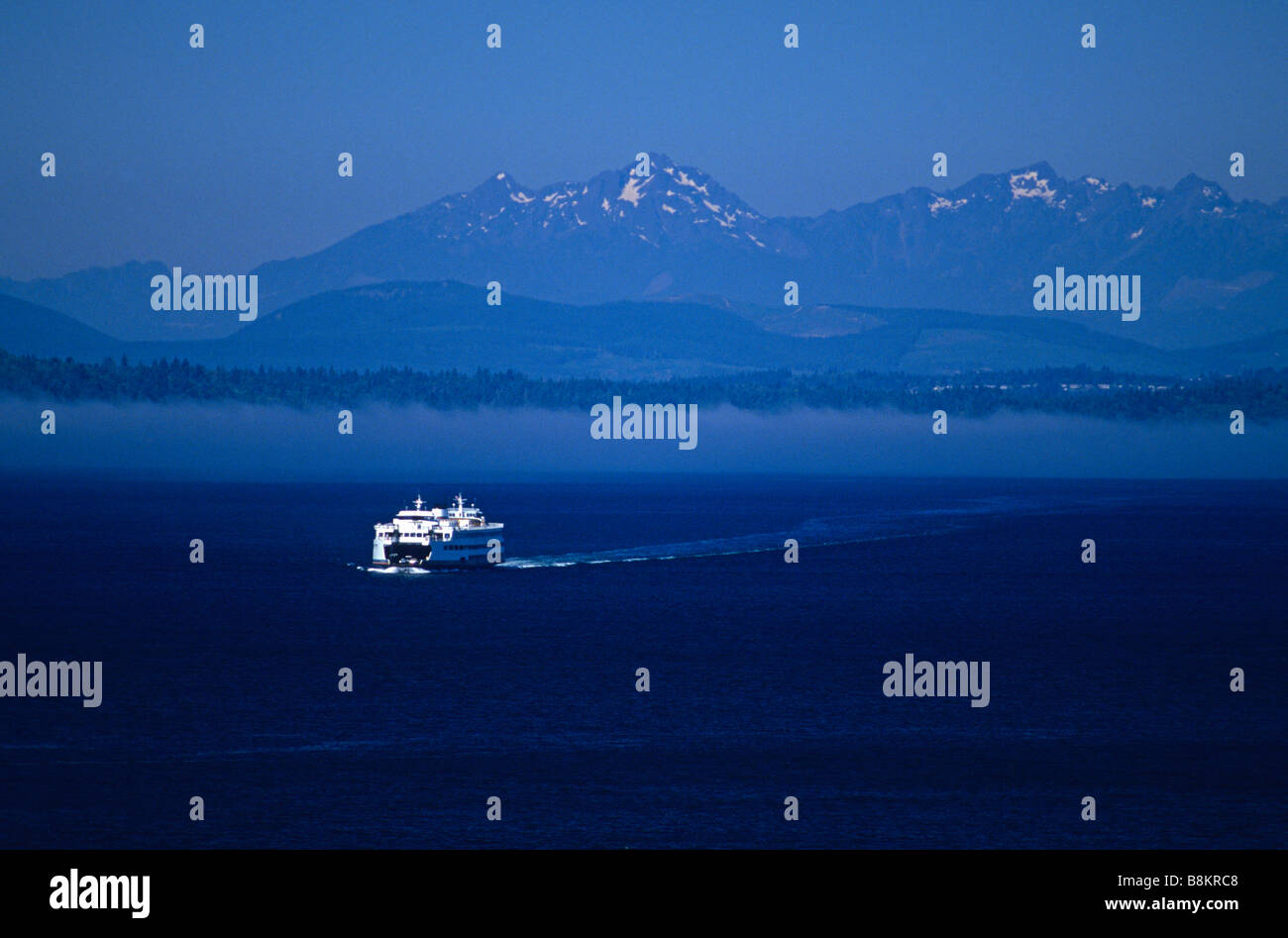 Ferry boat crossing waterway with Puget Sound and Olympic Mountains on ...