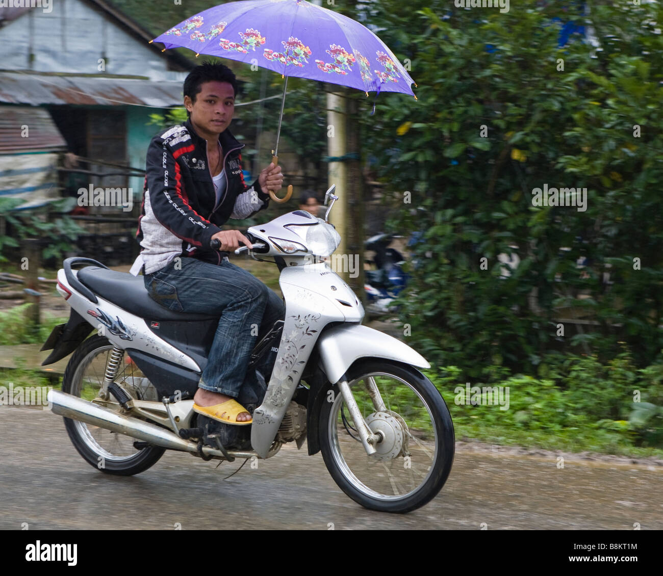 man on moped with umbrella Stock Photo - Alamy