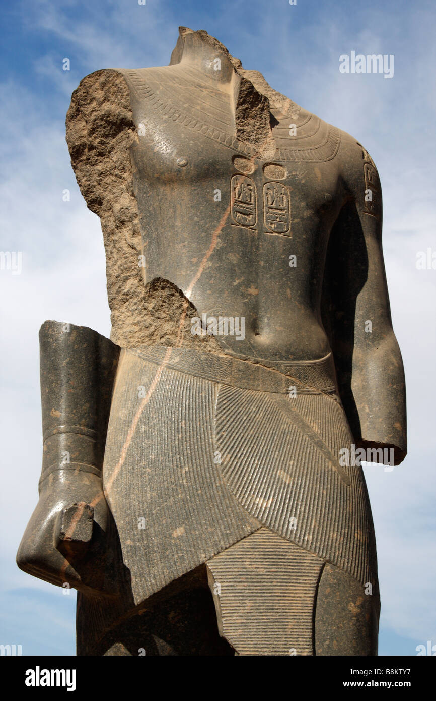 Headless stone statue of pharaoh against blue sky, Luxor Temple, Egypt ...