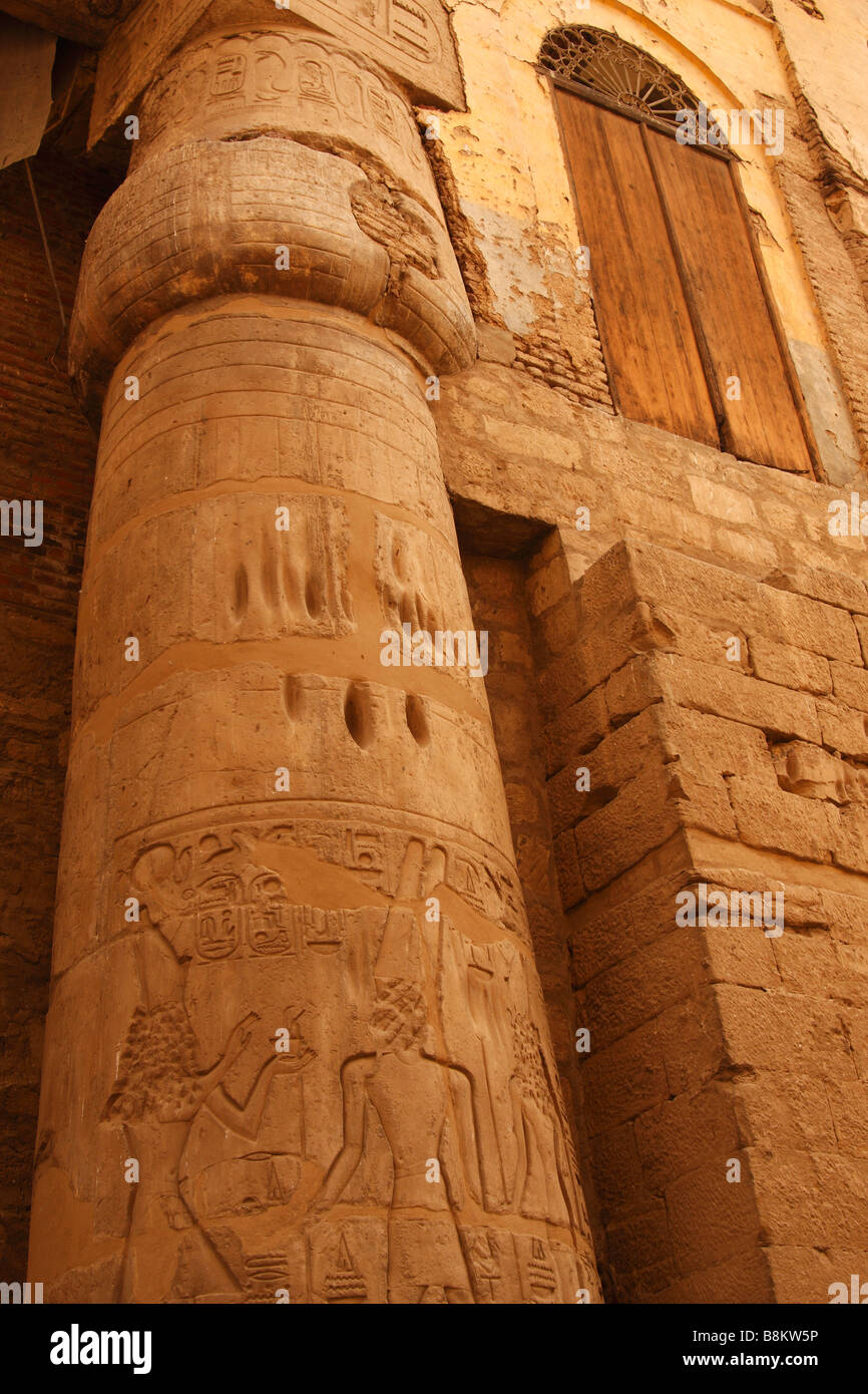 Large stone papyrus column with carved hieroglyphics next to old wooden ...