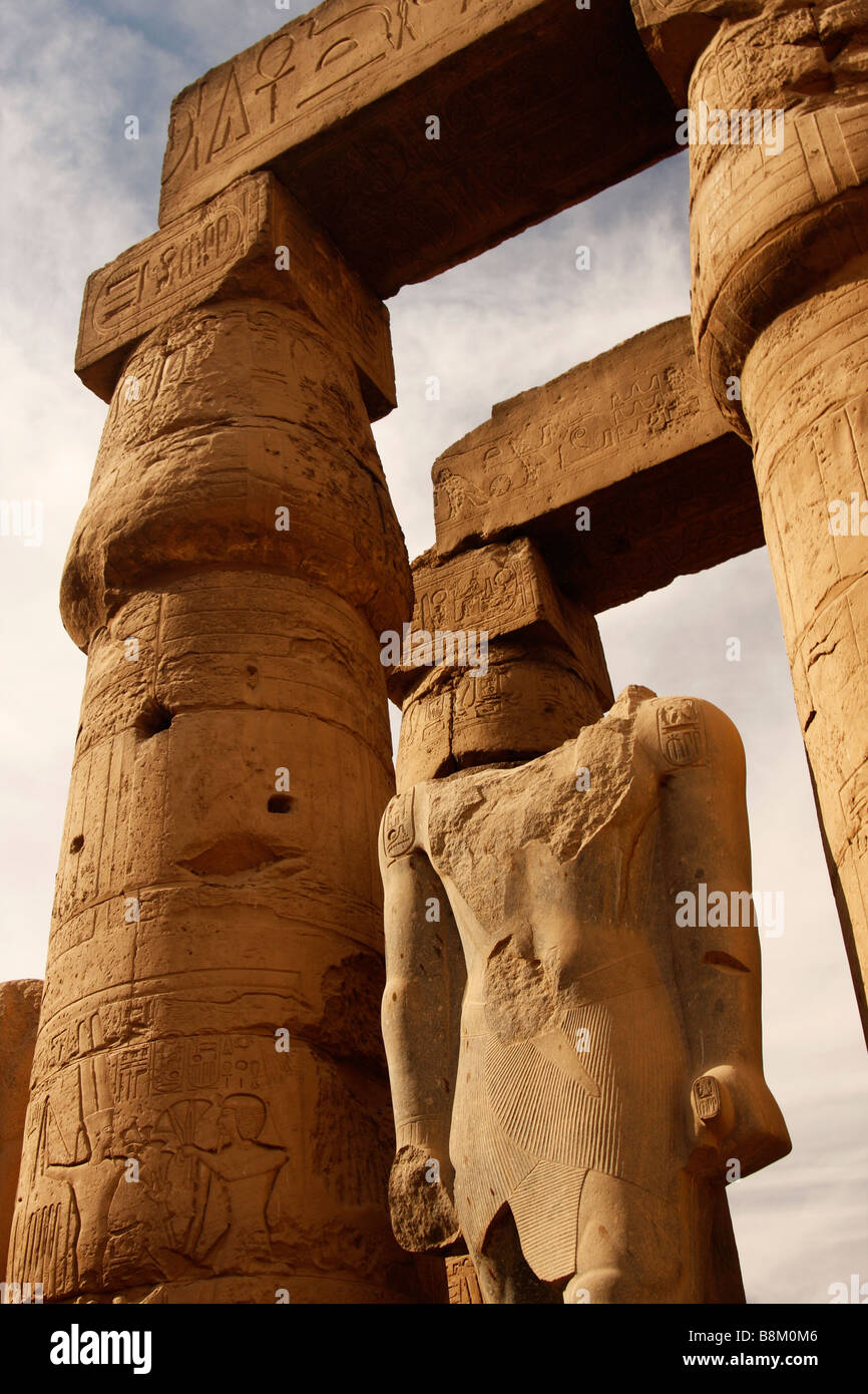 Headless statue of pharaoh beneath large stone carved papyrus columns ...