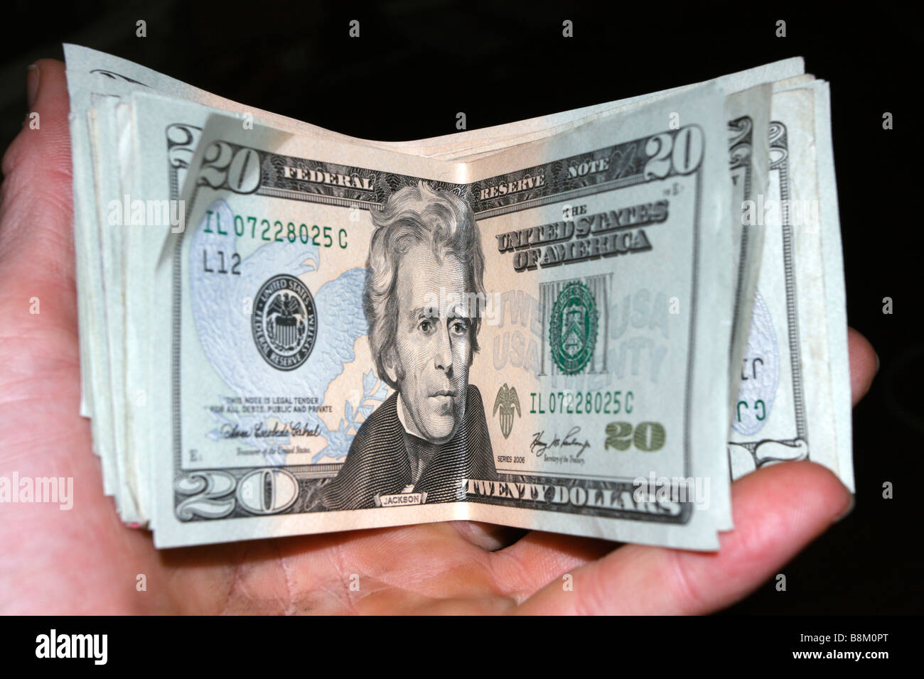 Hand holding USA twenty dollar bills on black Stock Photo - Alamy