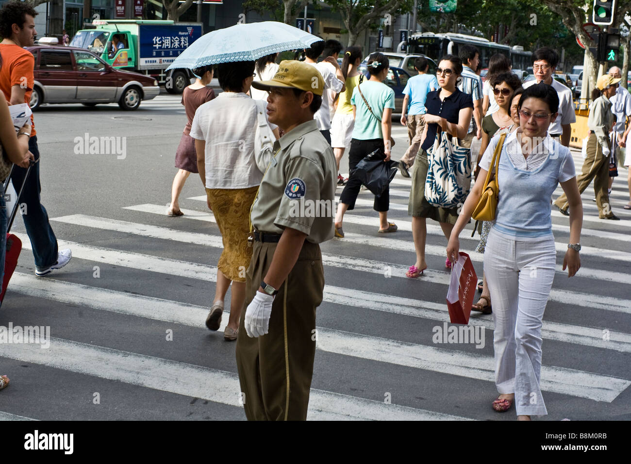 Traffic officer overseeing chinese pedestrians crossing a street in ...