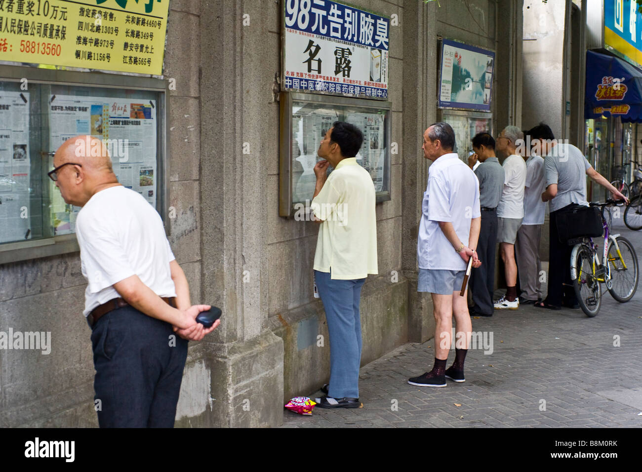 Concentrating on the latest news on an outdoor newspaper display board ...