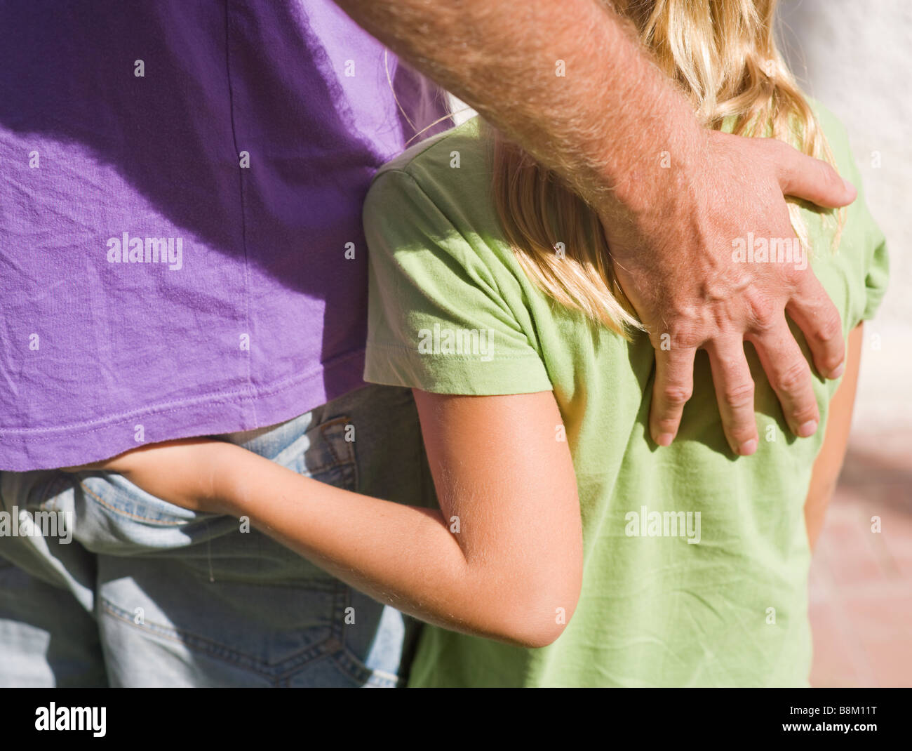 Eight years old girl with hand in back pocket of her father who has arm ...