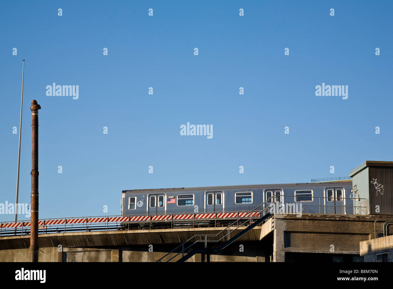 The Q subway train on an elevated rail against a blue sky at Coney ...