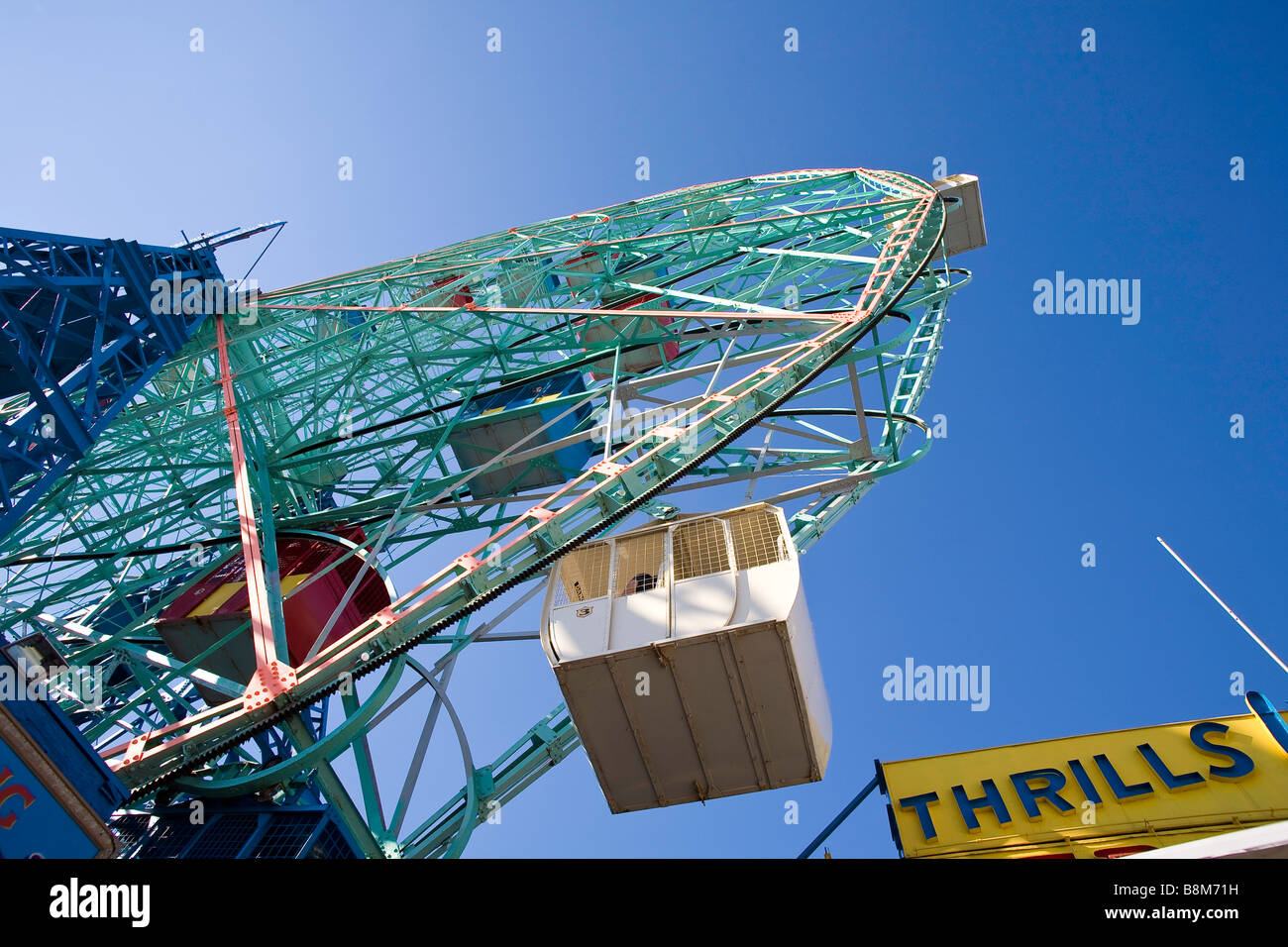 Ferris wheel against a blue sky with carnival sign reading "Thrills" in ...