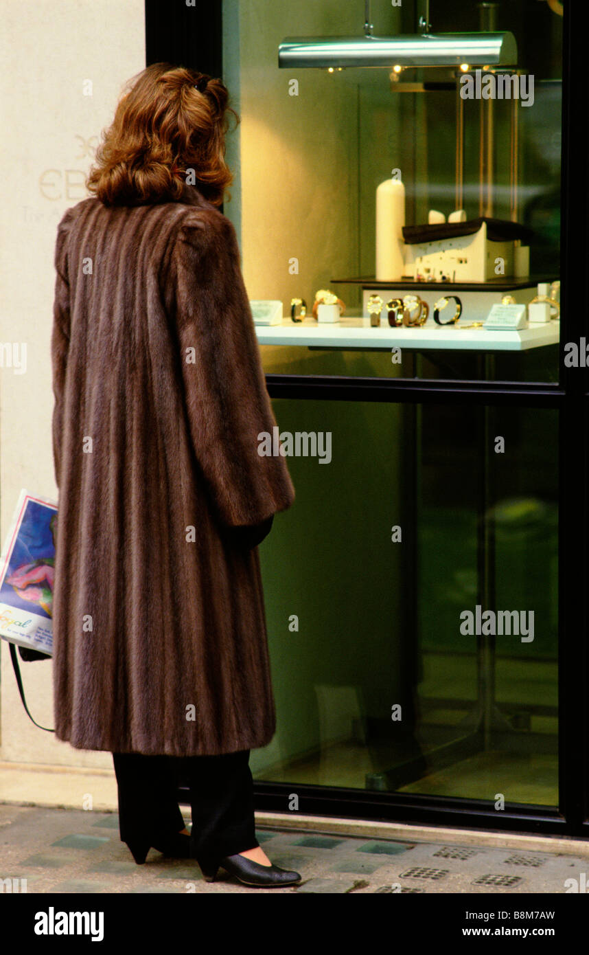 London UK A woman wearing a large fur coat looks at expensive watches ...