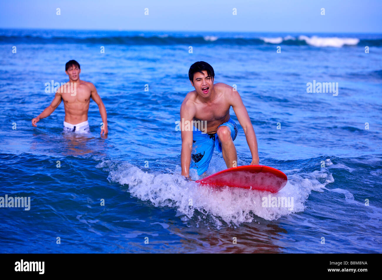 Man helping young man surfing on the sea Stock Photo - Alamy