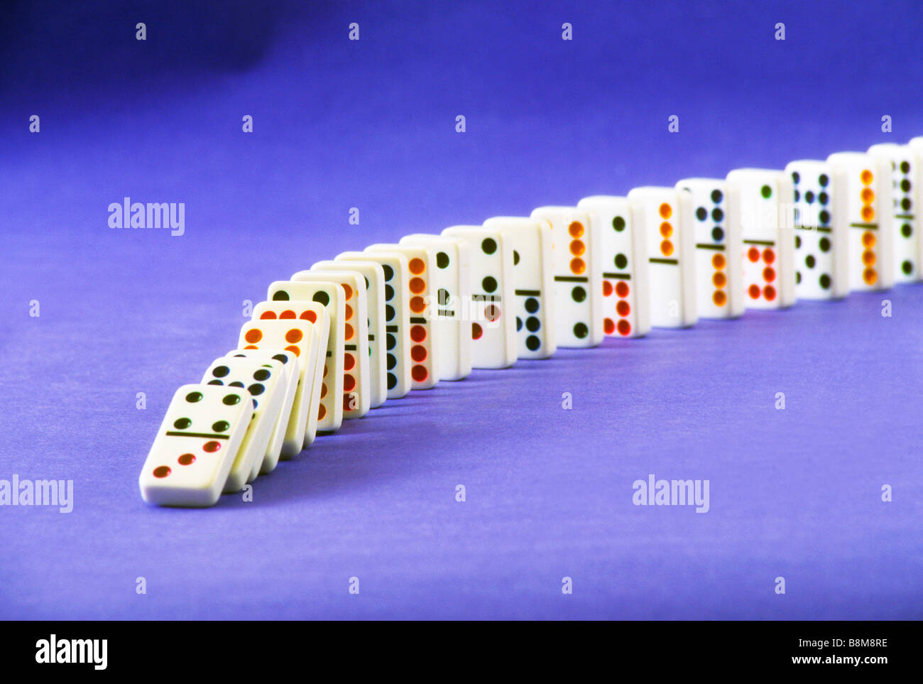 Dominos fall in row in domino effect Stock Photo - Alamy