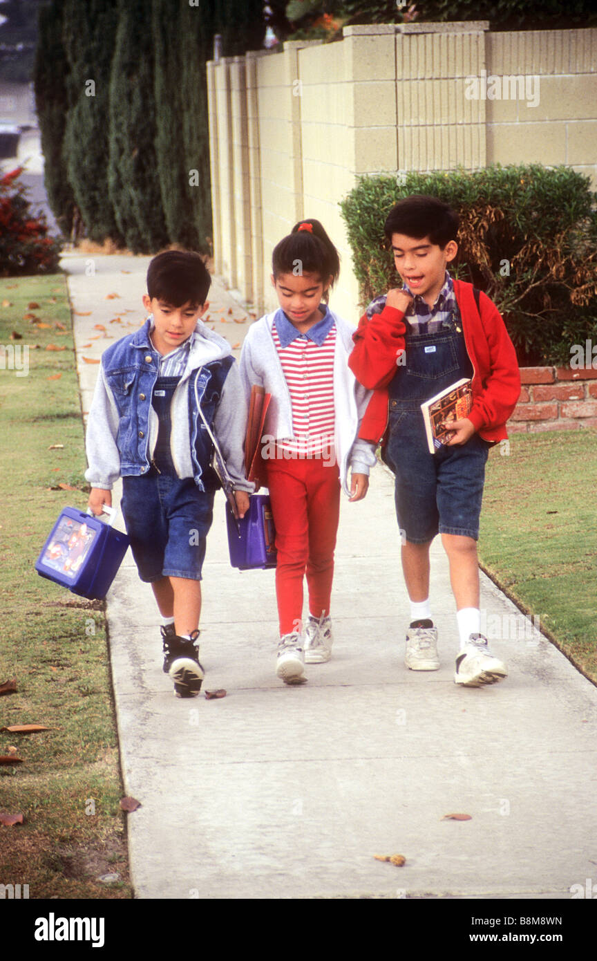 Three Hispanic kids talk as they walk home from school Stock Photo - Alamy