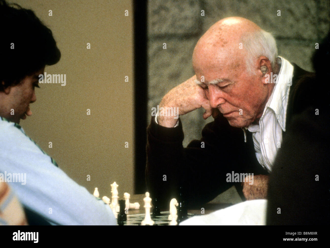 Senior man deep in thought plays chess with teen boy Stock Photo - Alamy