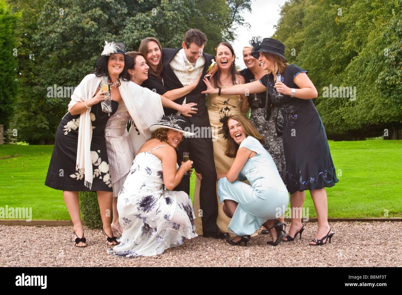 Horizontal informal group portrait of a groom on his wedding day being ...