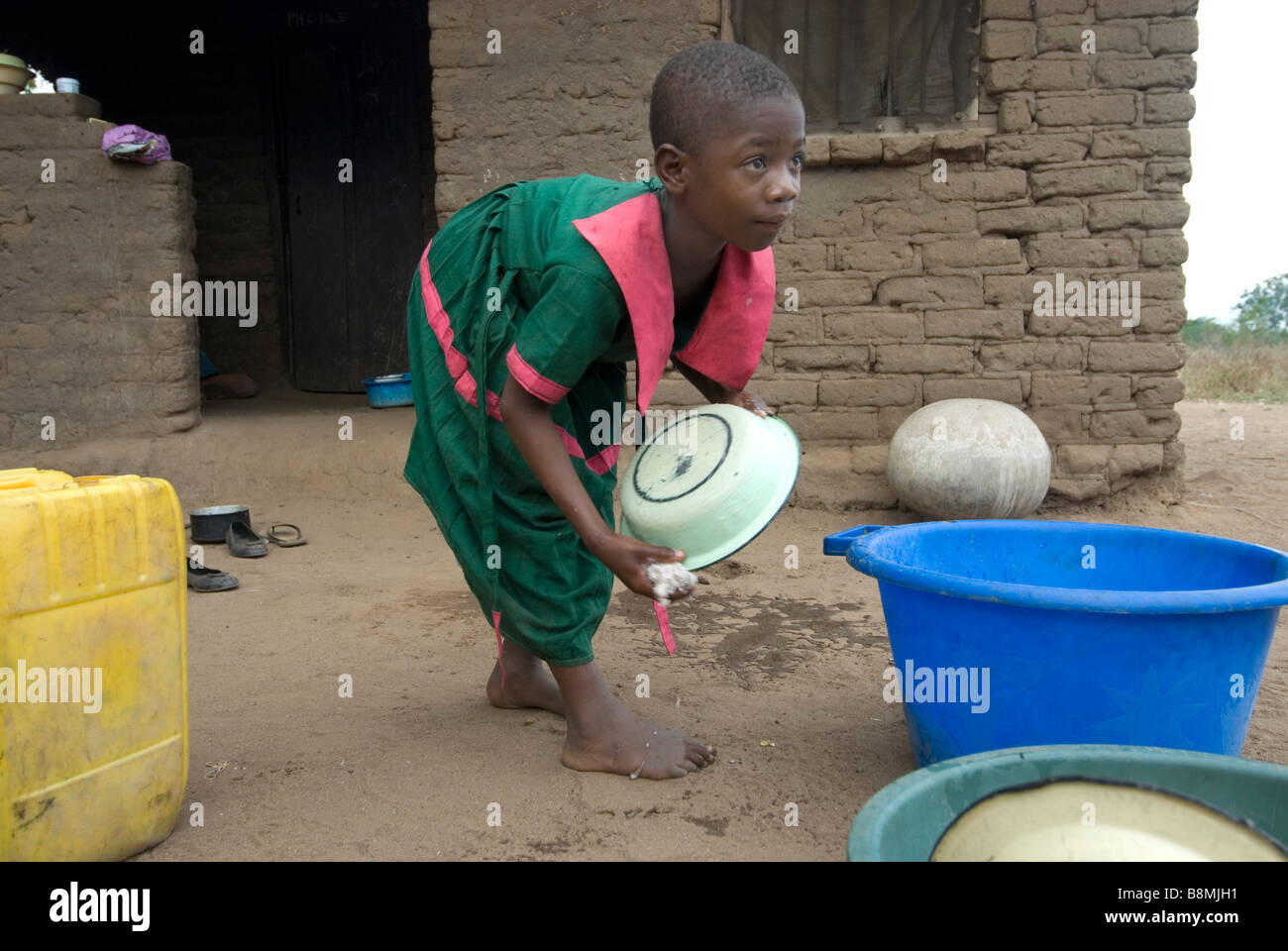 Malawi 2008 Maria Bishop 7 washes the dishes in front of her home Stock ...