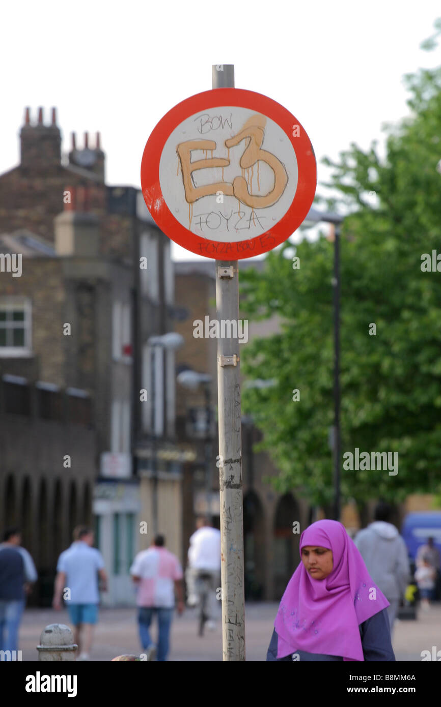 A young Bangladeshi girl wearing a Hajib scarf walks past a road sign ...