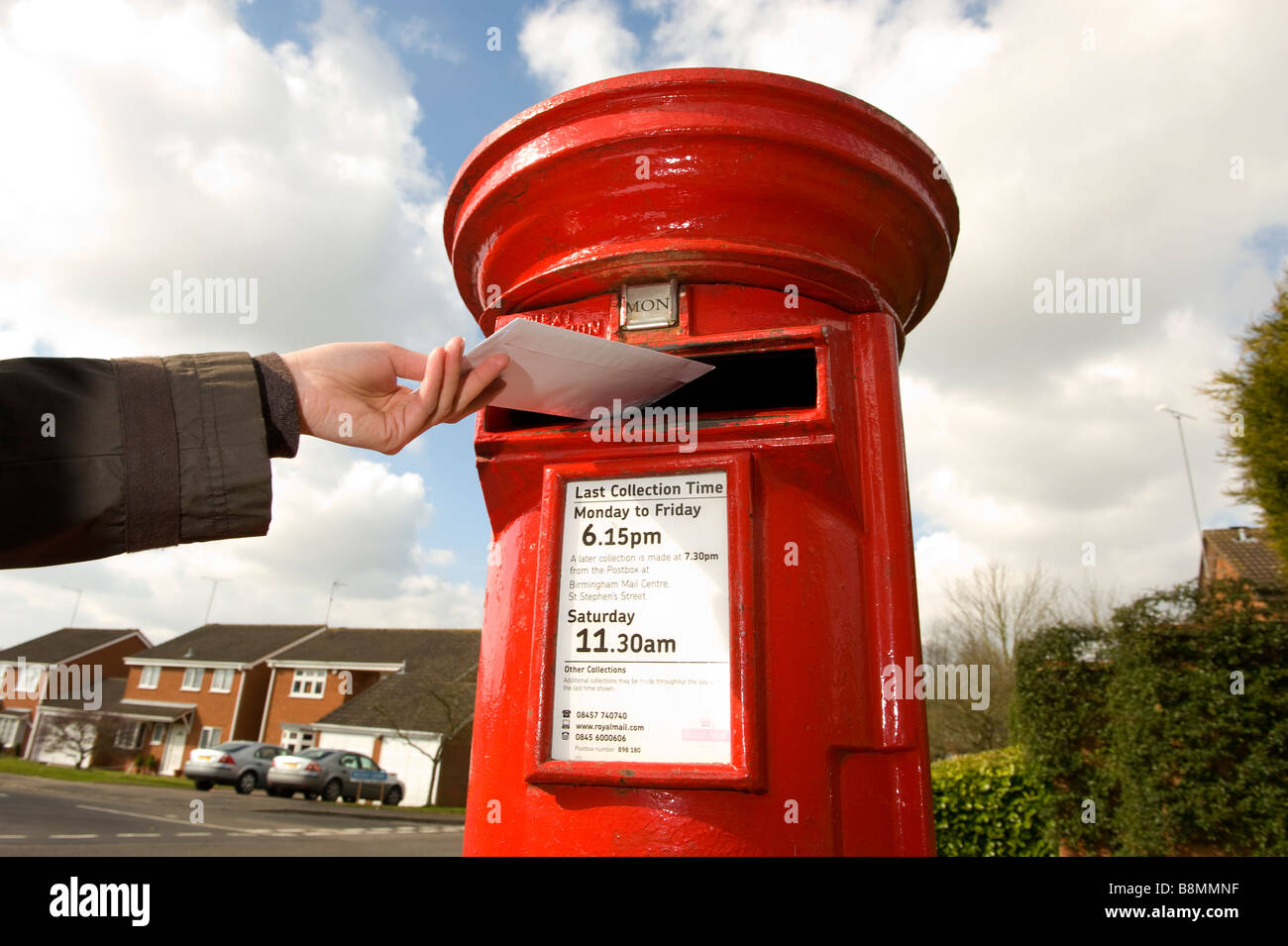 A letter is posted into a bright red Royal Mail post box in ...