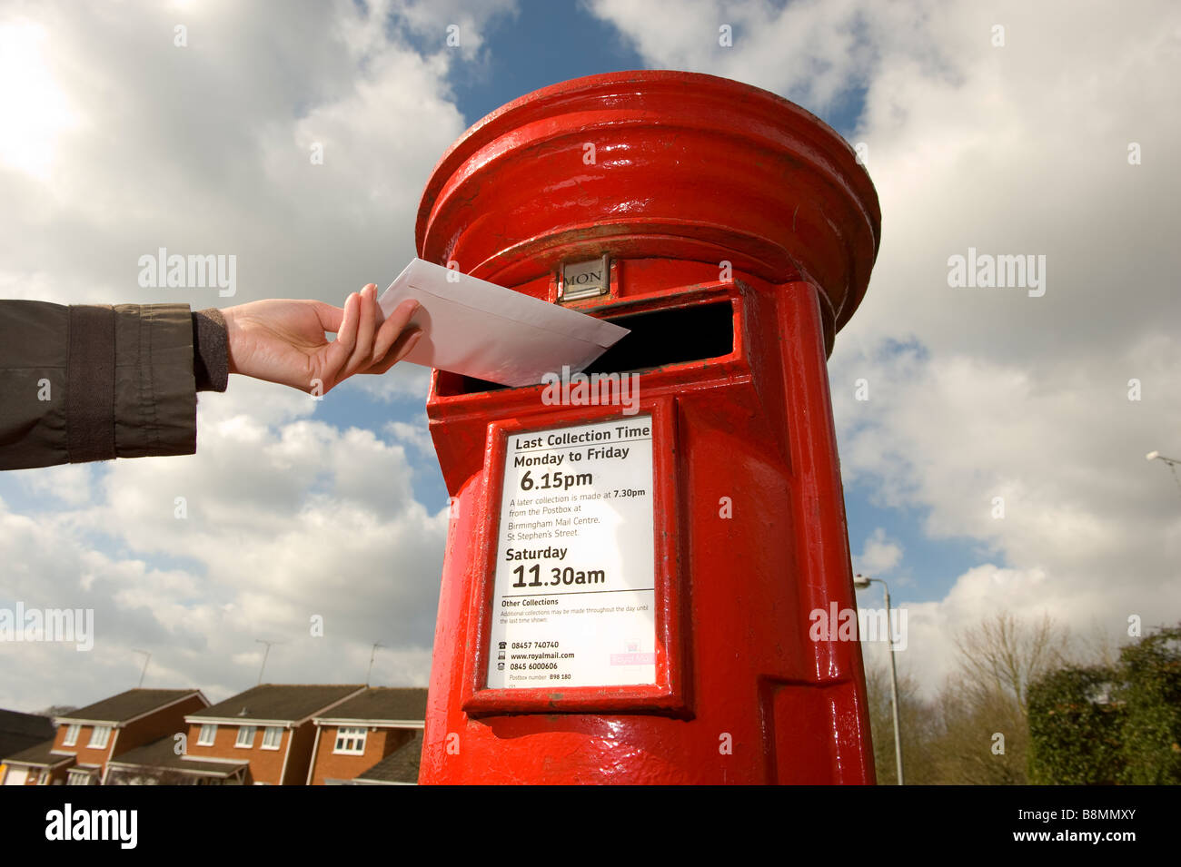 A letter is posted into a bright red Royal Mail post box in ...