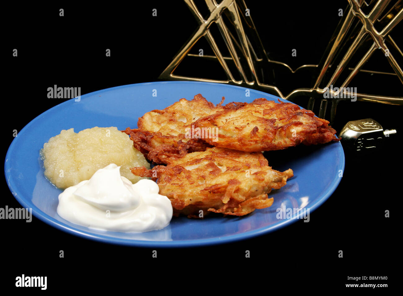 Potato latkes for Hanukah with a menorah and a dreidel on a black ...