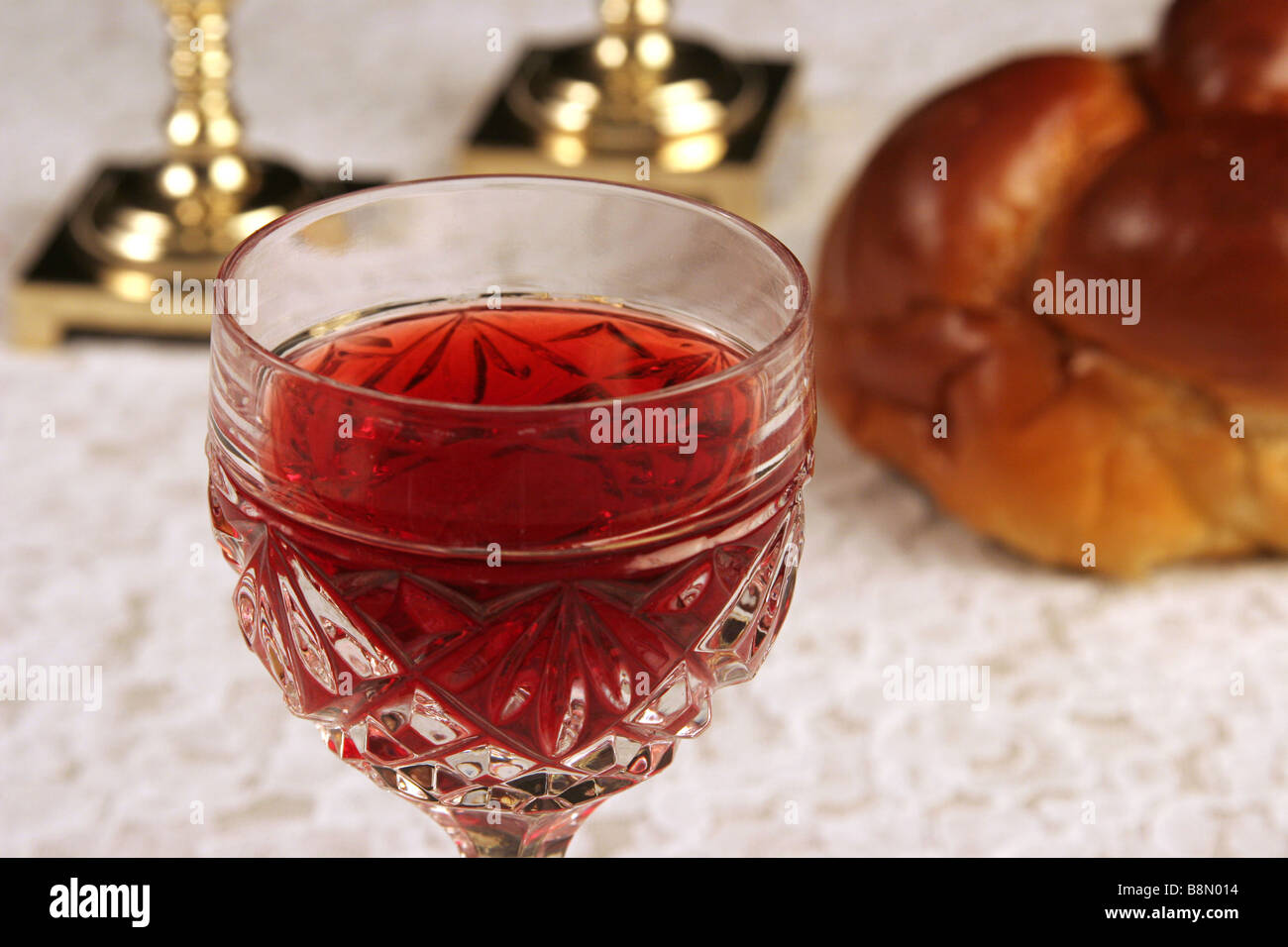 A glass of wine for Shabbat with candlesticks and challah in the ...