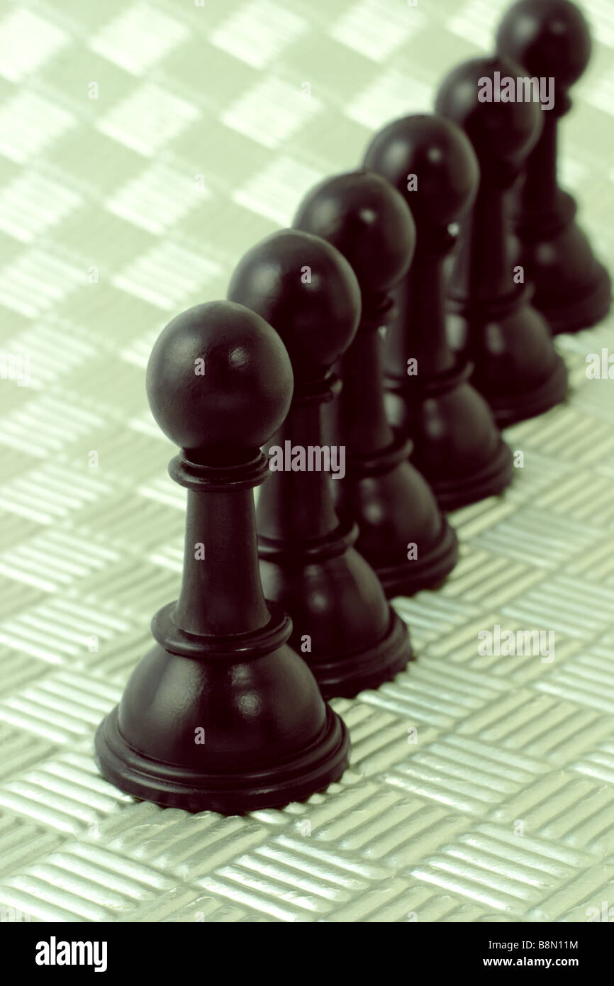 Row of black pawns arranged on off white metallic background Stock ...