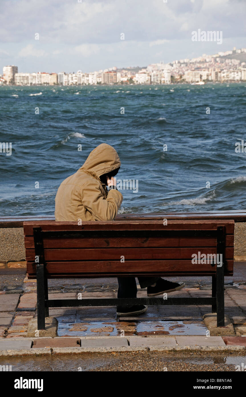 Man sit sitting on his own on a bench face look looking facing aegean ...