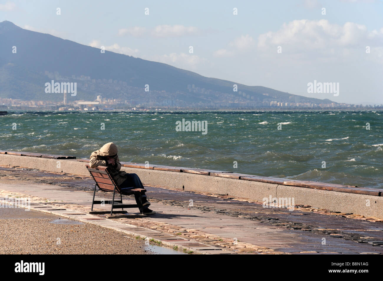 Man sit sitting on his own on a bench face look looking facing aegean ...