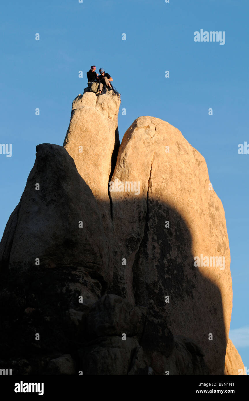 two rock climbers man and woman getting ready to descend from top of a ...