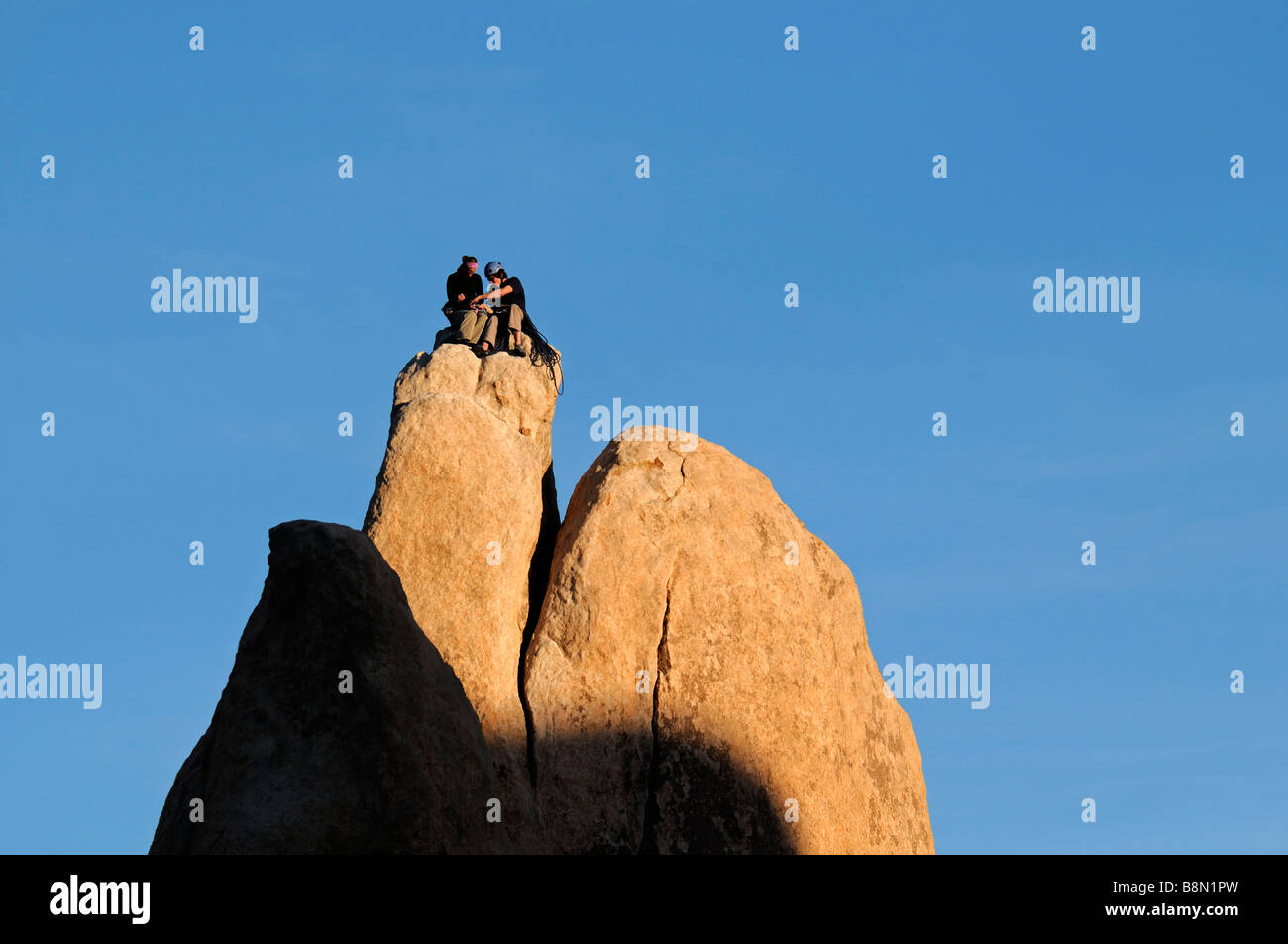 two rock climbers man and woman getting ready to descend from top of a ...