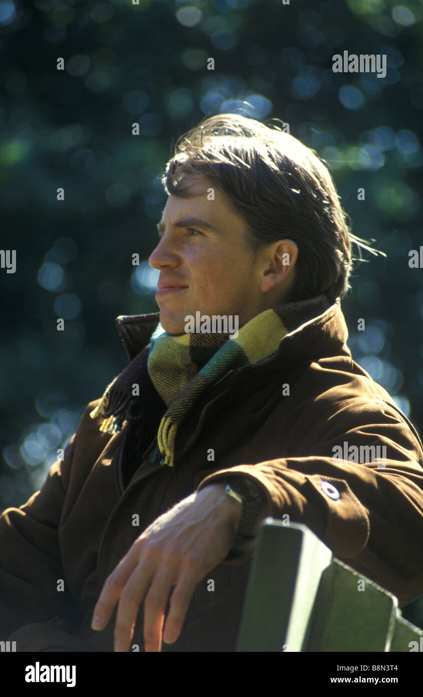 young man sitting outside on a park bench looking moody Stock Photo - Alamy