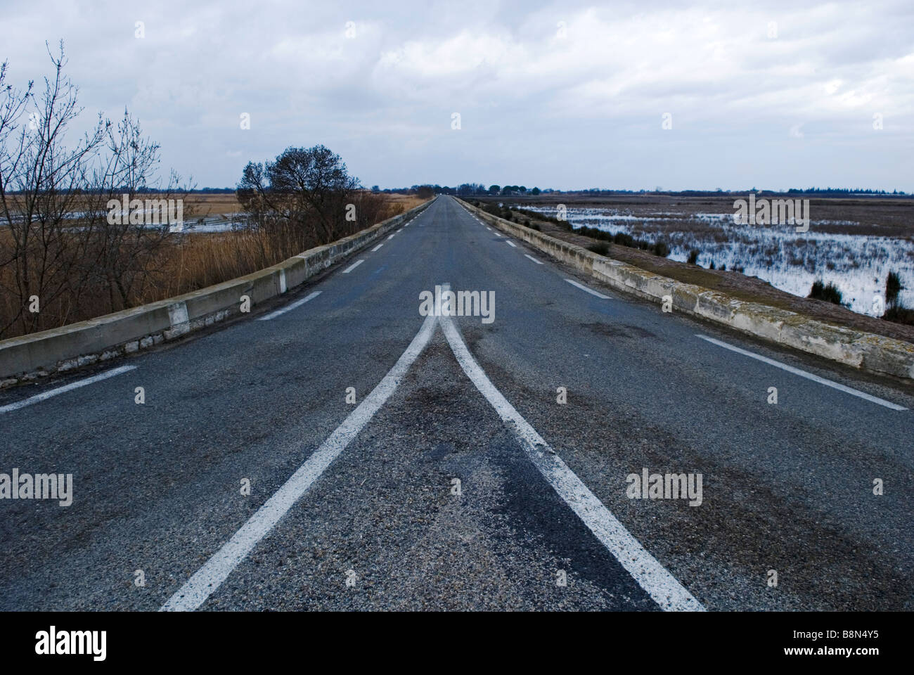 looking down the middle of a straight two laned road going across ...
