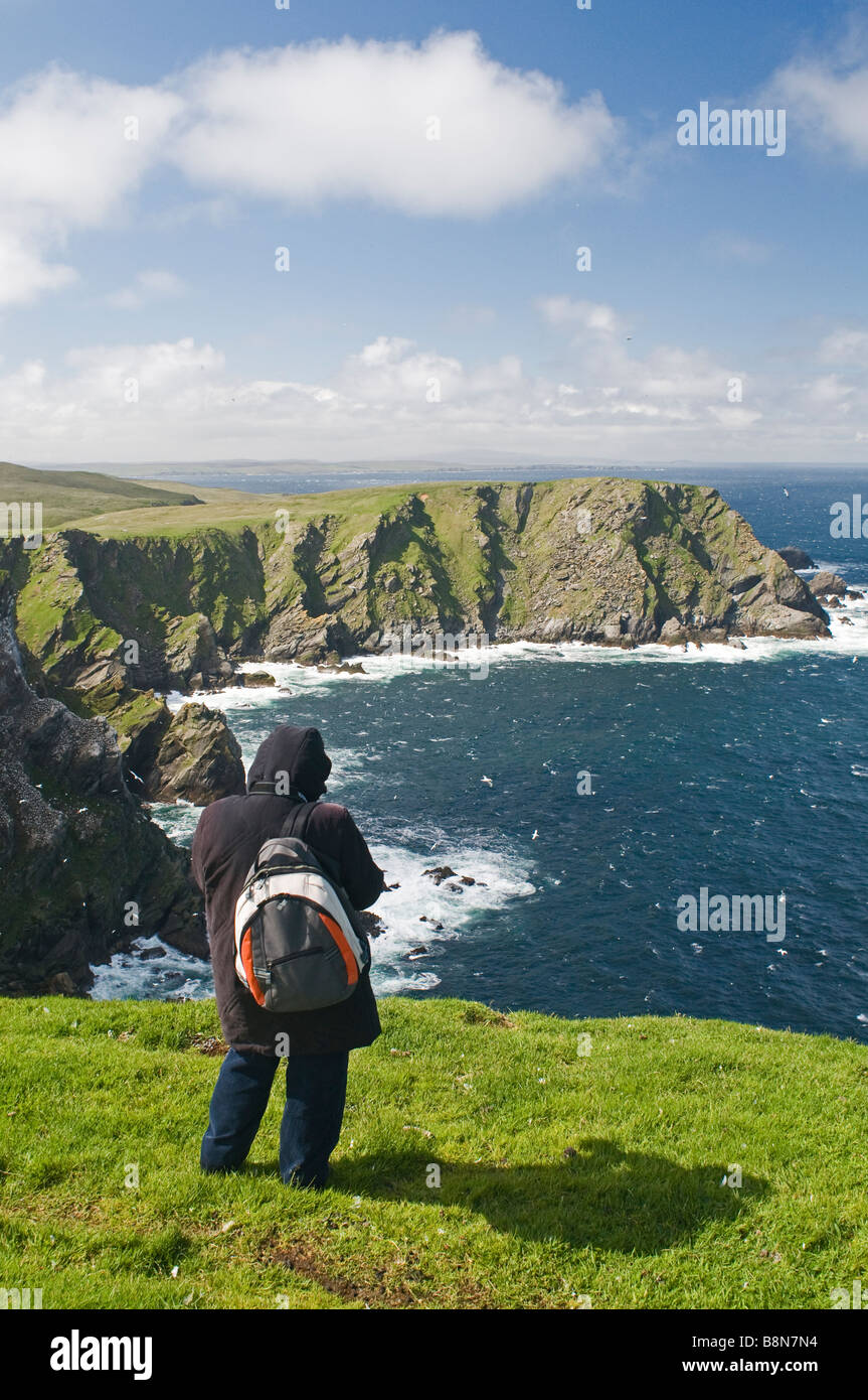 walker looking out across sea cliffs at Hermaness NNR on Unst Shetland ...