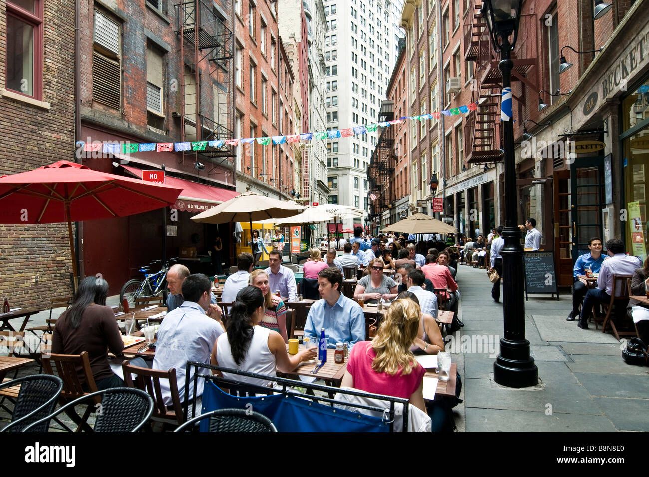 Street scene with people having lunch at a casual outdoor restaurant ...