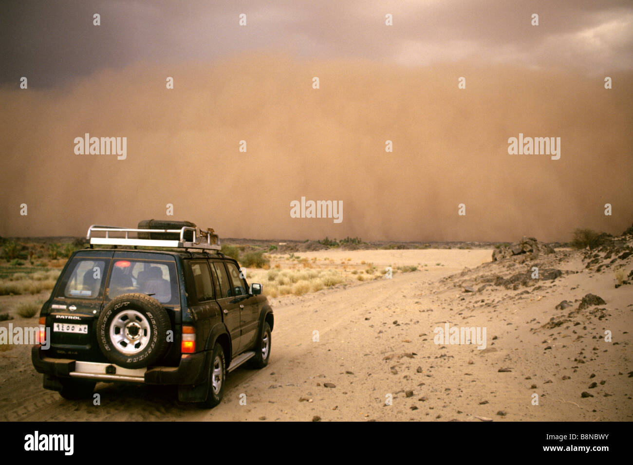 Vehicle in the desert with approaching sandstorm Stock Photo - Alamy