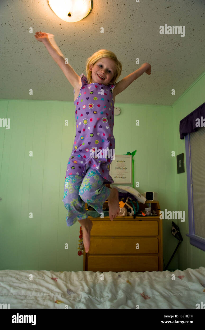 Young girl jumping on a bed in a bedroom with green walls Stock Photo ...