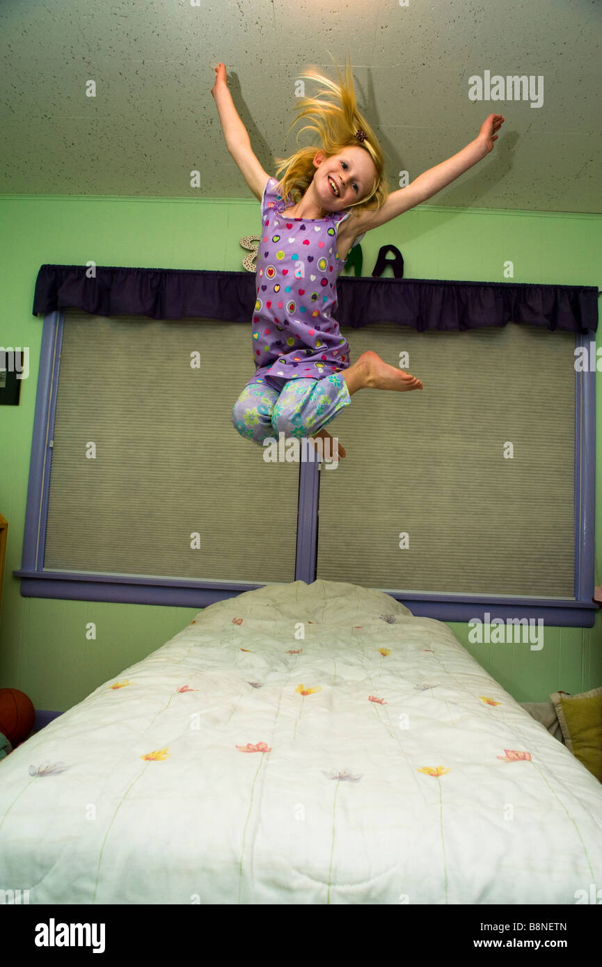 Young girl jumping on a bed in a bedroom with green walls Stock Photo ...