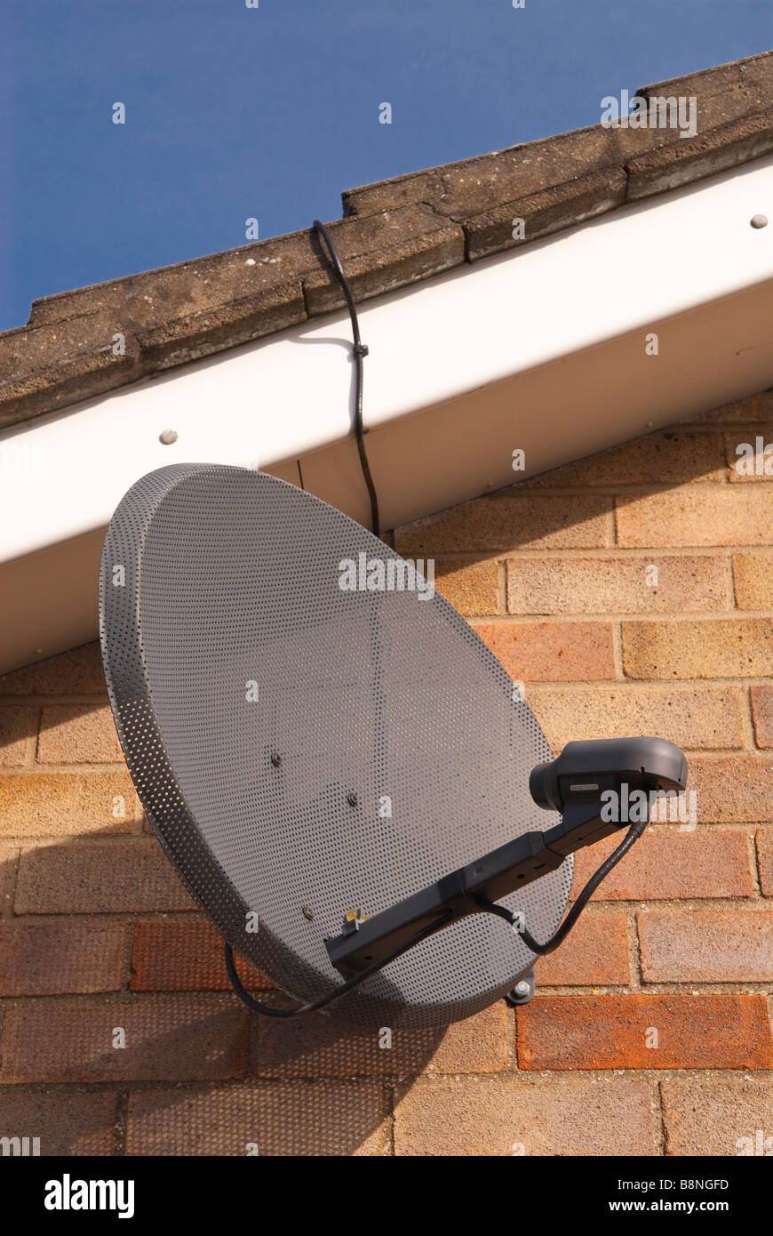 A satelite tv television dish fitted on the exterior wall of a house ...