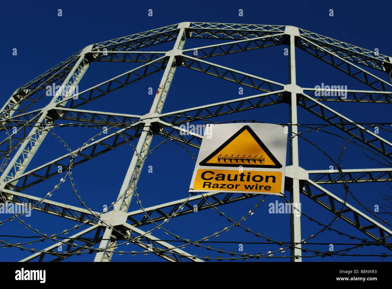 "Caution razor wire" sign on gas station against blue sky, New Barnet ...
