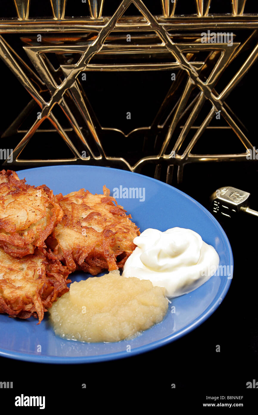 Potato latkes for Hanukah with a menorah dreidel on a black background ...