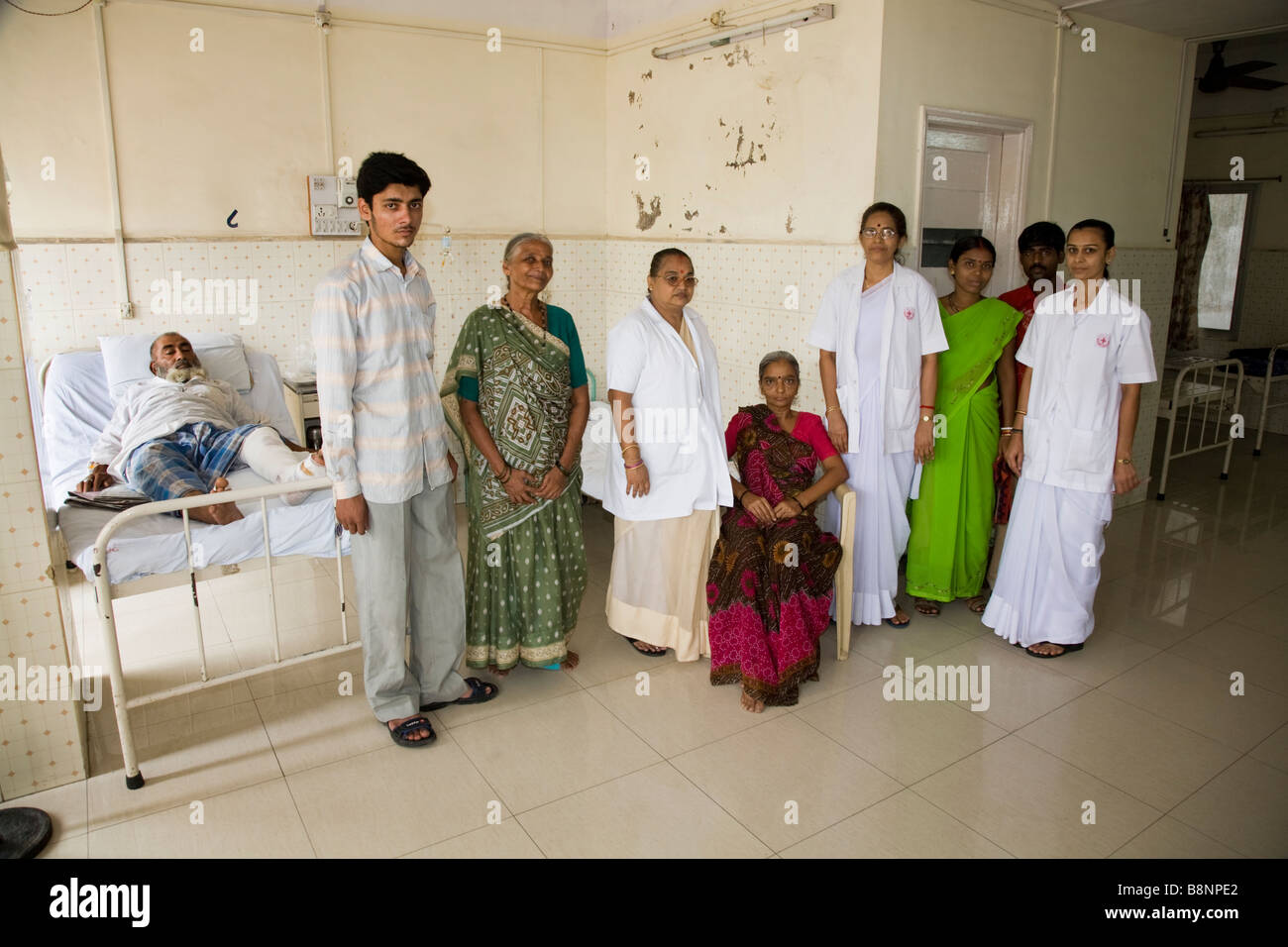 A bed ridden patient with family members and nursing staff in a general ...
