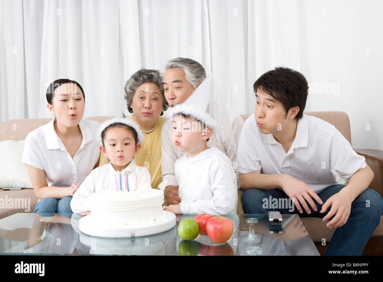 Three generation family blowing birthday cake Stock Photo - Alamy