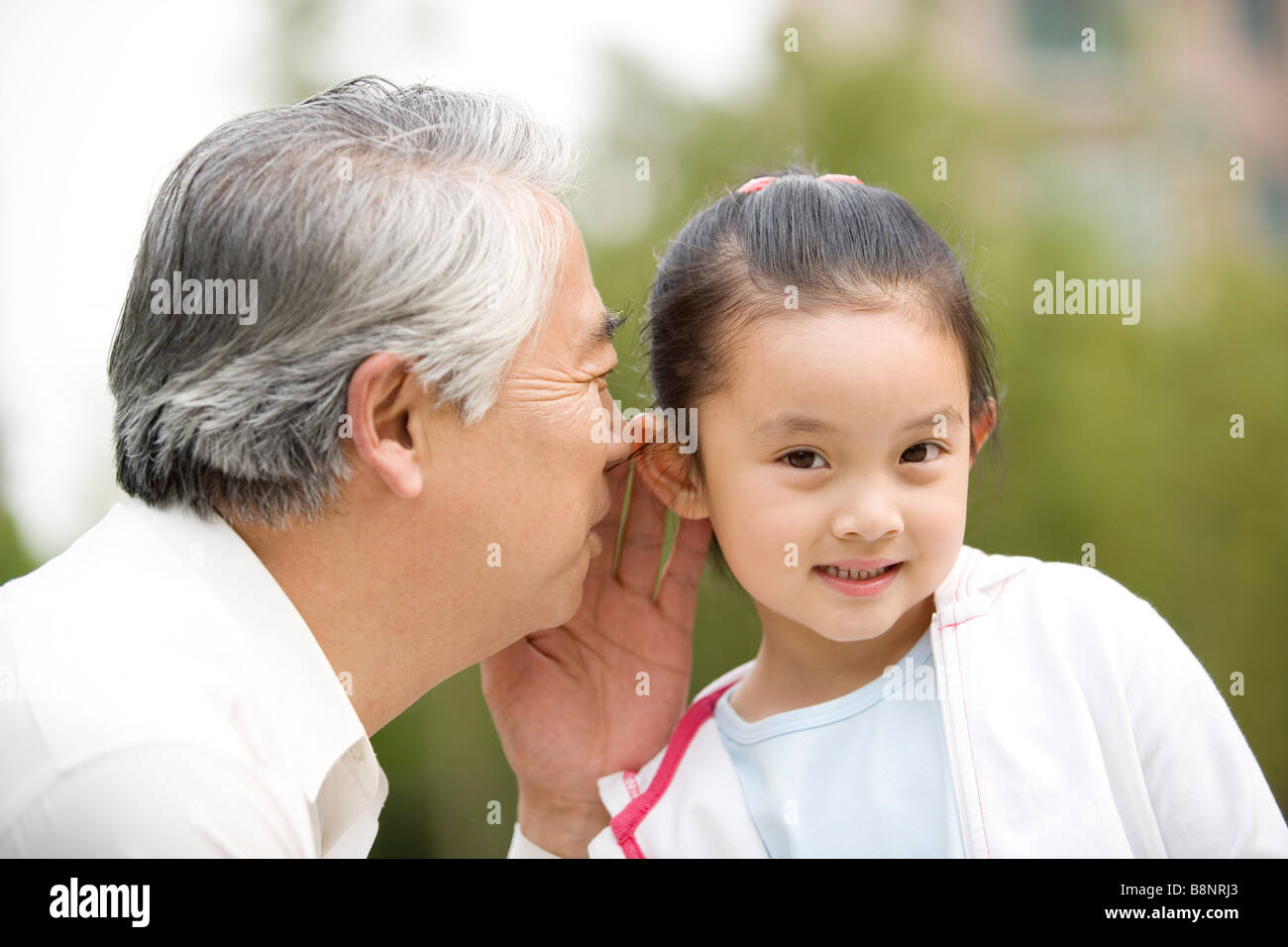 Grandfather whispering in granddaughter s ear Stock Photo - Alamy