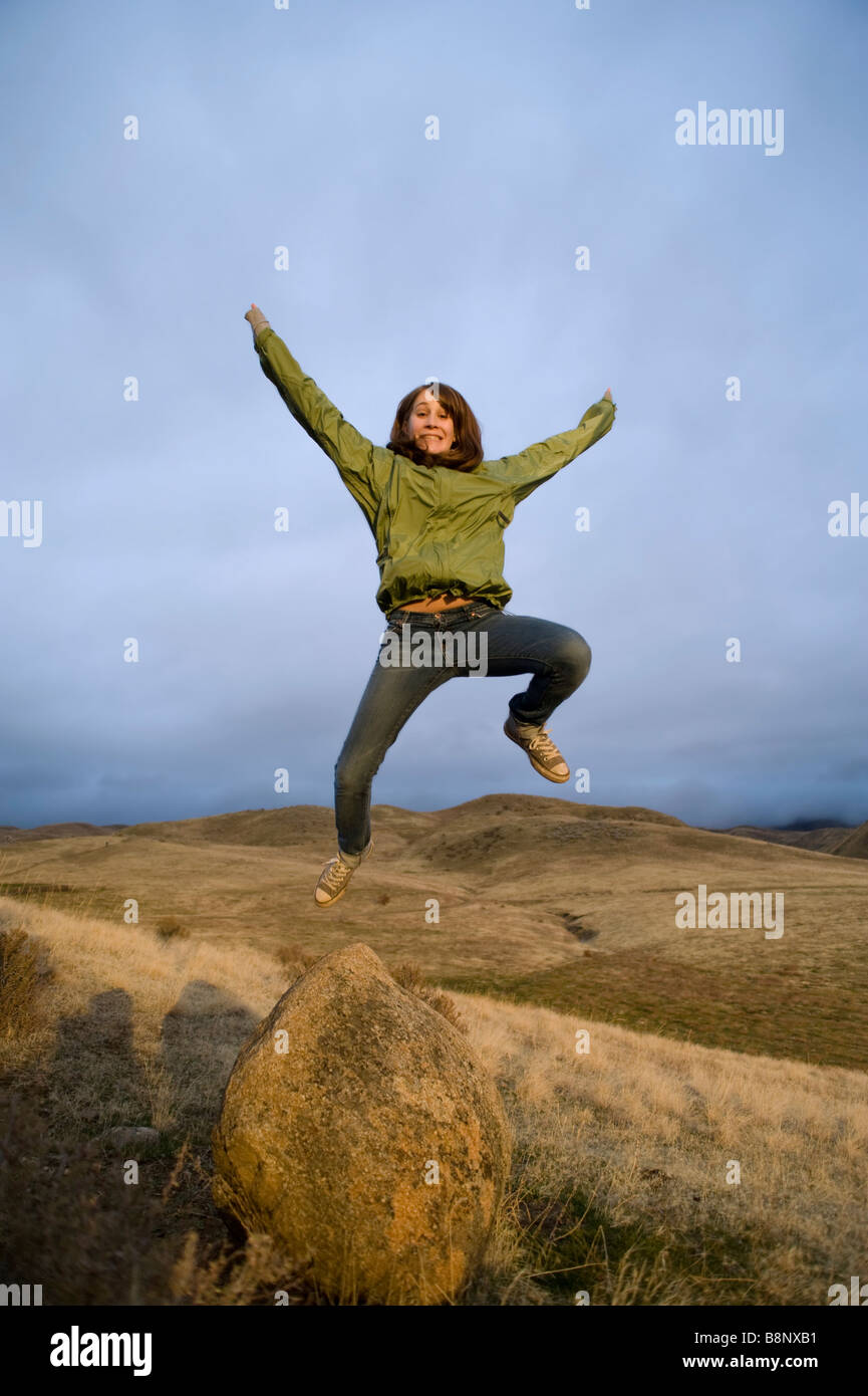 Teenage girl jumping from a rock with her arms outspread Stock Photo ...