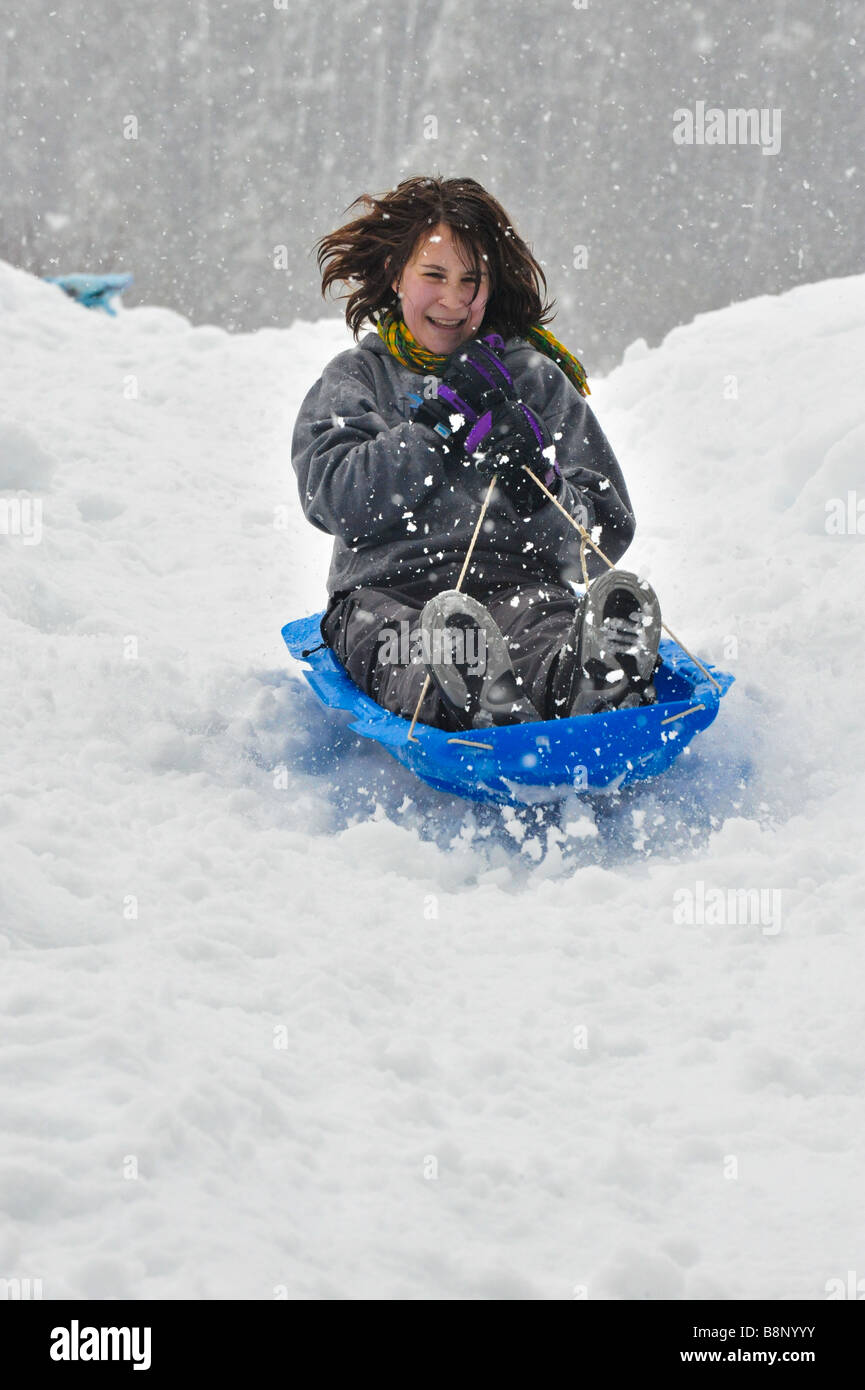 Teenage girl sledding in the snow on a saucer Stock Photo - Alamy