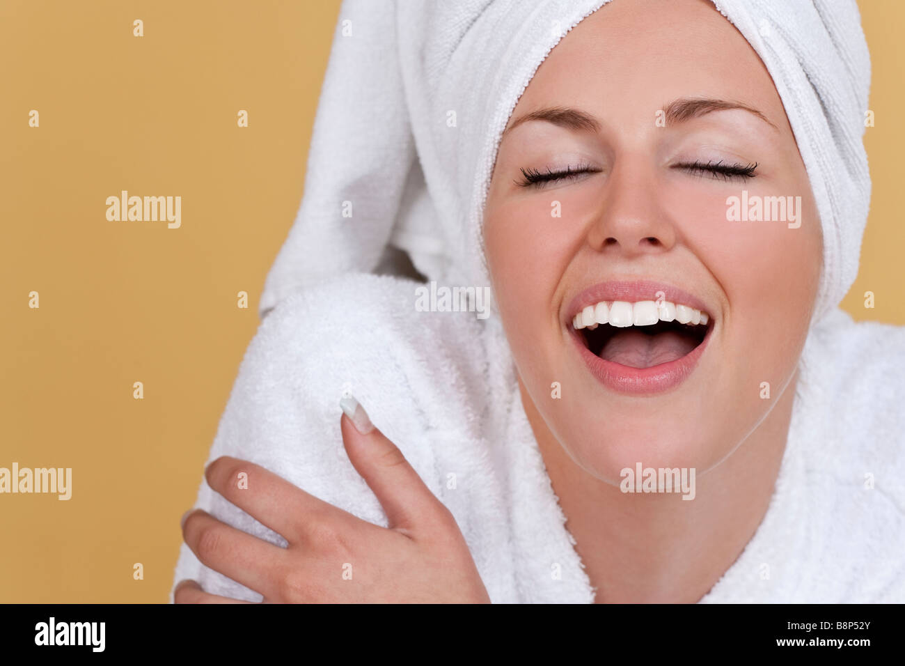 A beautiful young woman in a toweling robe and her hair in a towel ...