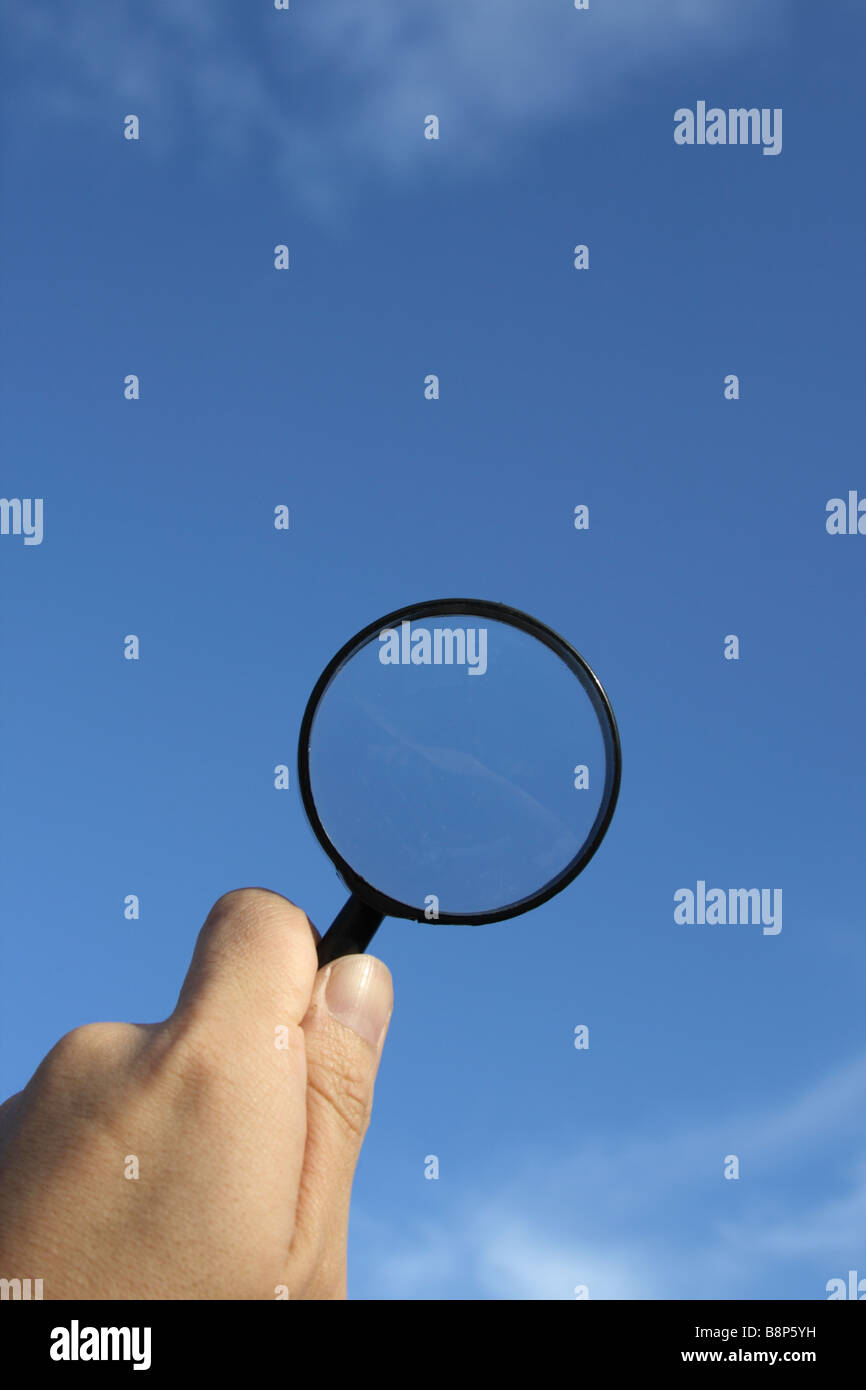 hand holding magnifying glass against blue sky Stock Photo - Alamy